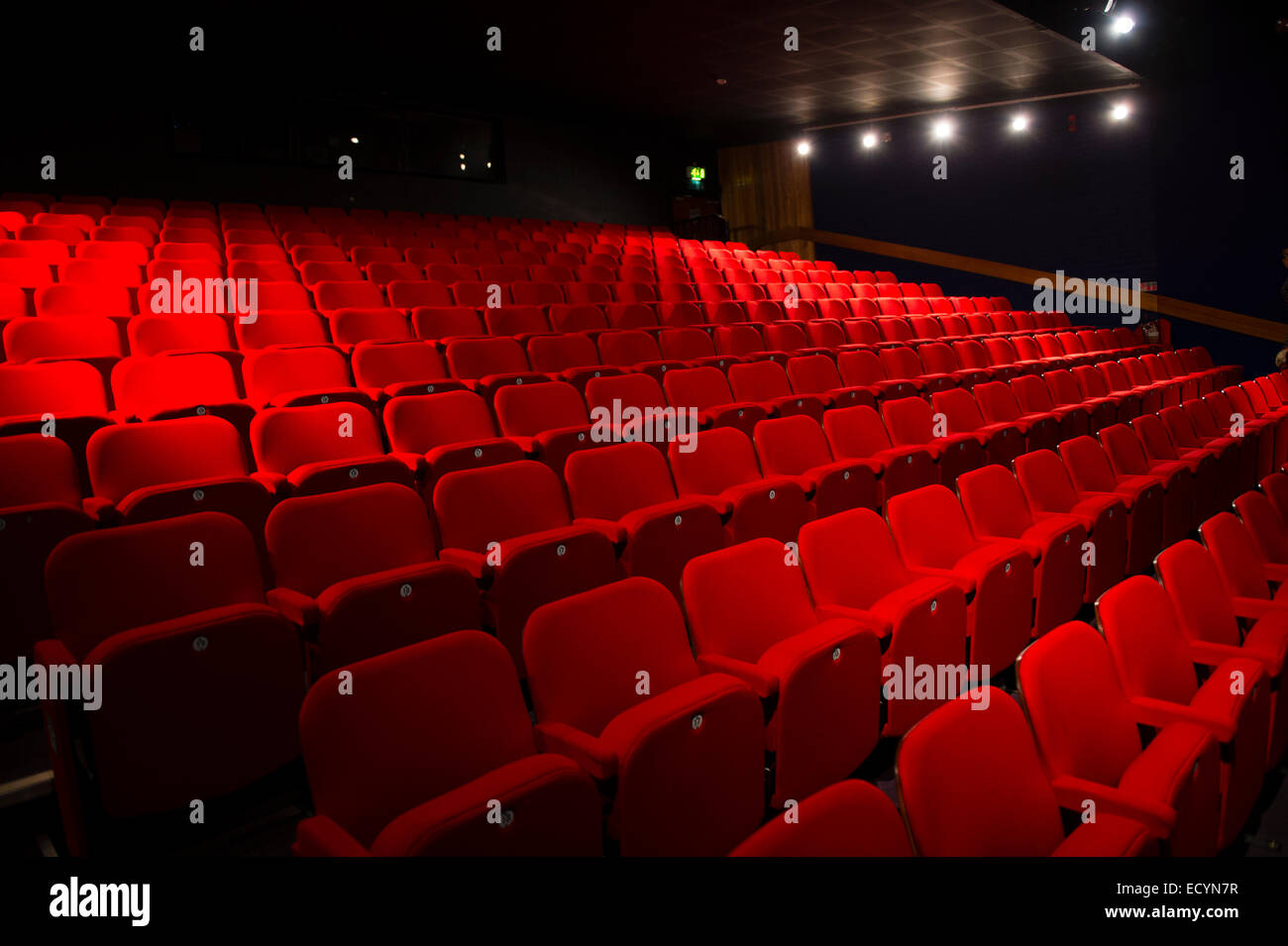 Rows of empty red seats in a small theatre before the audience arrives ...