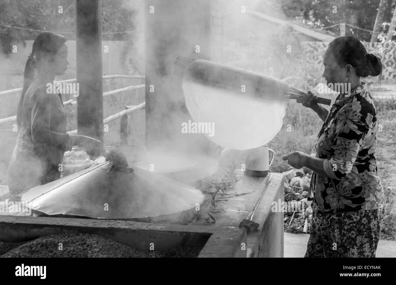 Vietnamese family working in their small home factory making rice paper ...