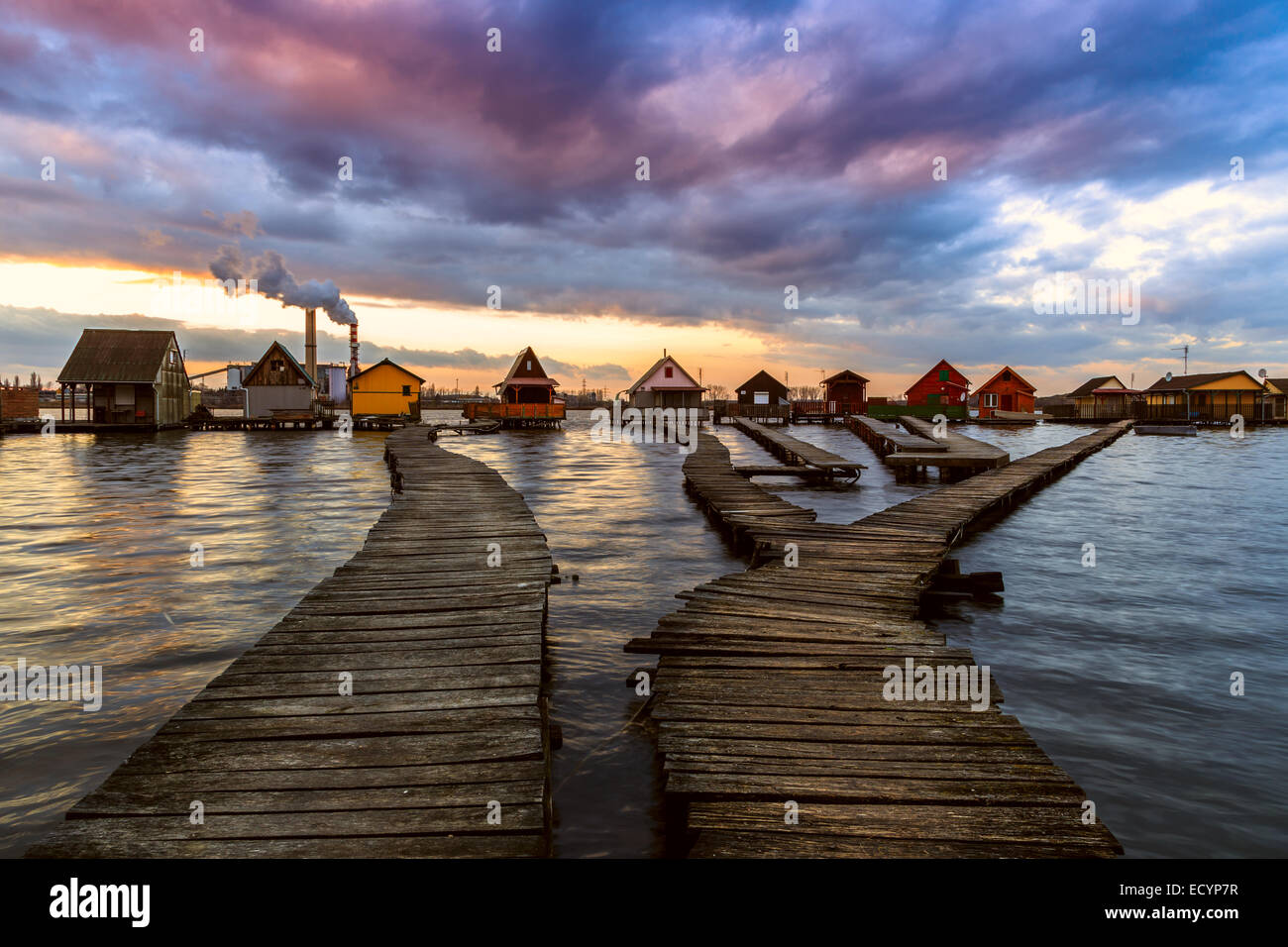Sunset lake Bokod with pier and fishing wooden cottages, power plant in ...
