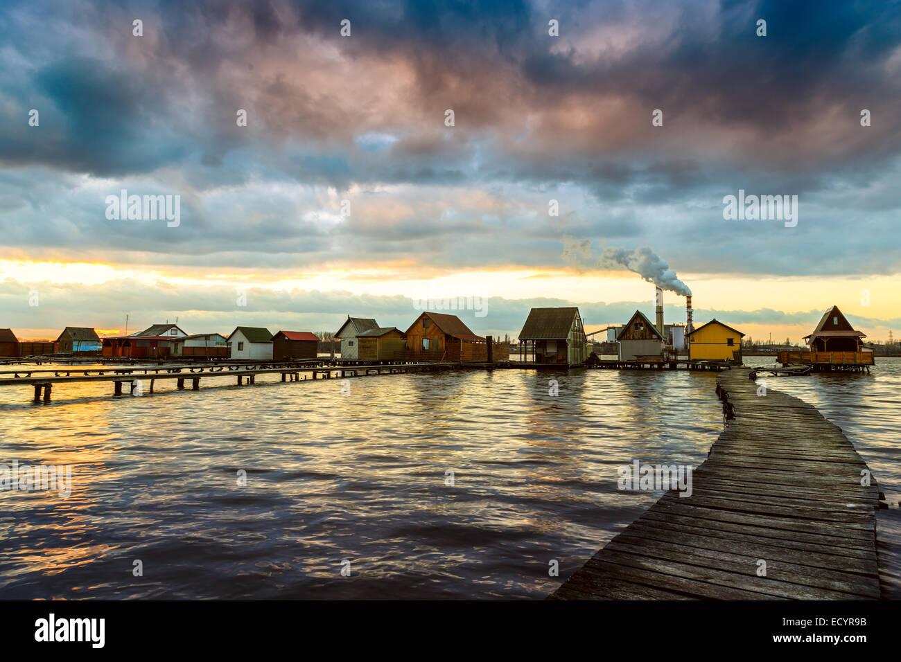 Sunset lake Bokod with pier and fishing wooden cottages, power plant in ...