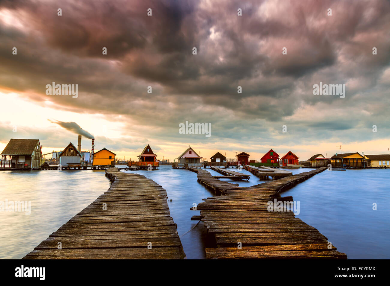 Sunset lake Bokod with pier and fishing wooden cottages, power plant in ...