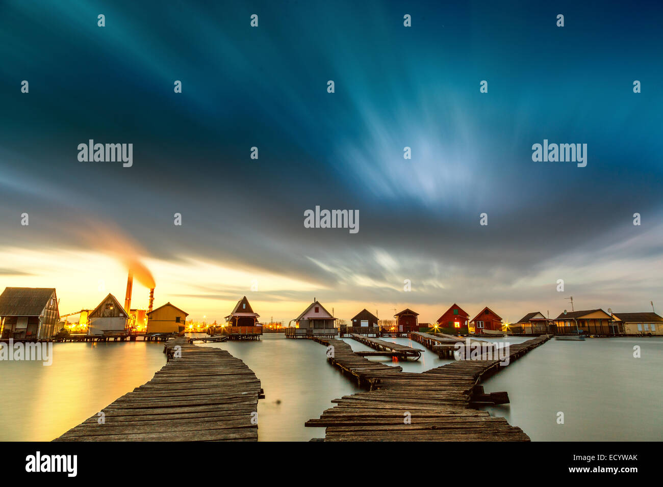 Sunset lake Bokod with pier and fishing wooden cottages, power plant in ...