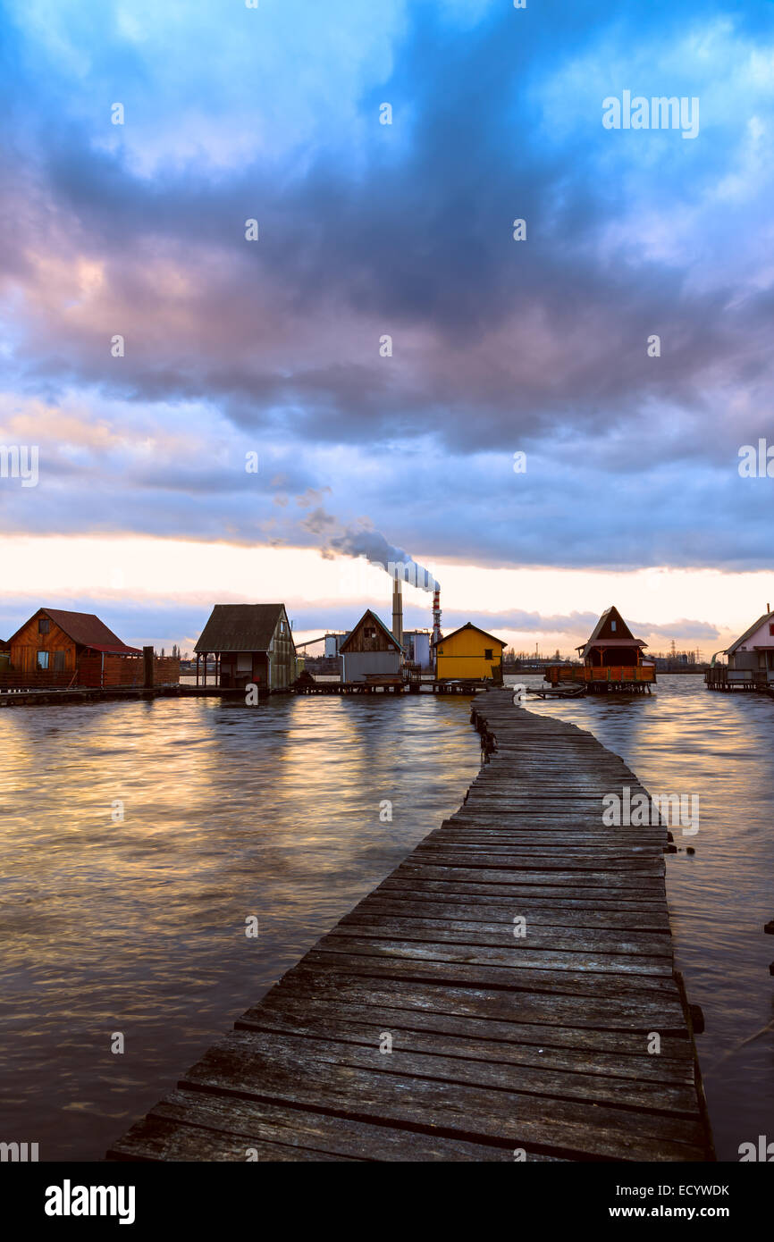 Sunset lake Bokod with pier and fishing wooden cottages, power plant in ...