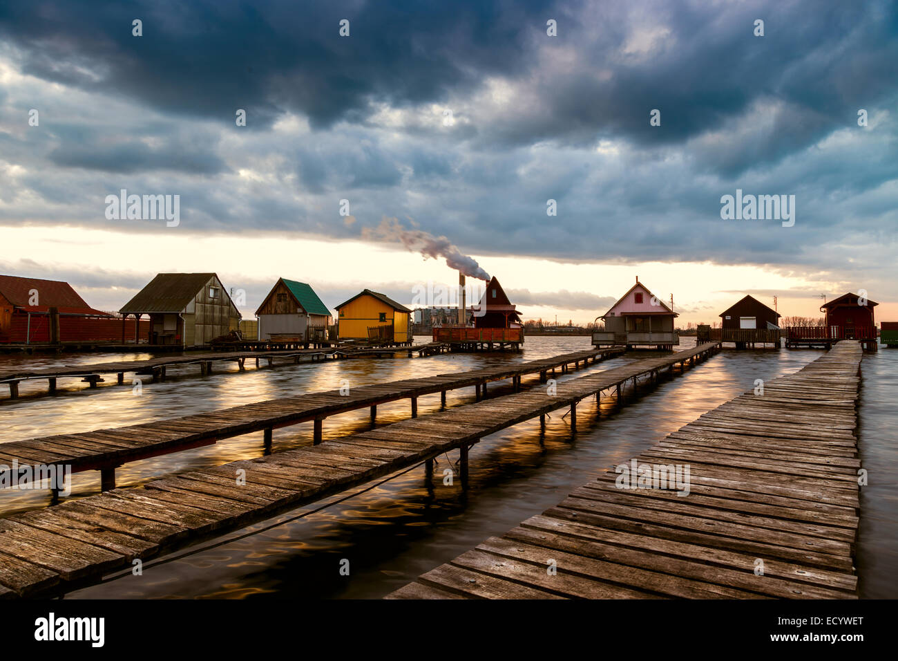 Sunset lake Bokod with pier and fishing wooden cottages, power plant in ...