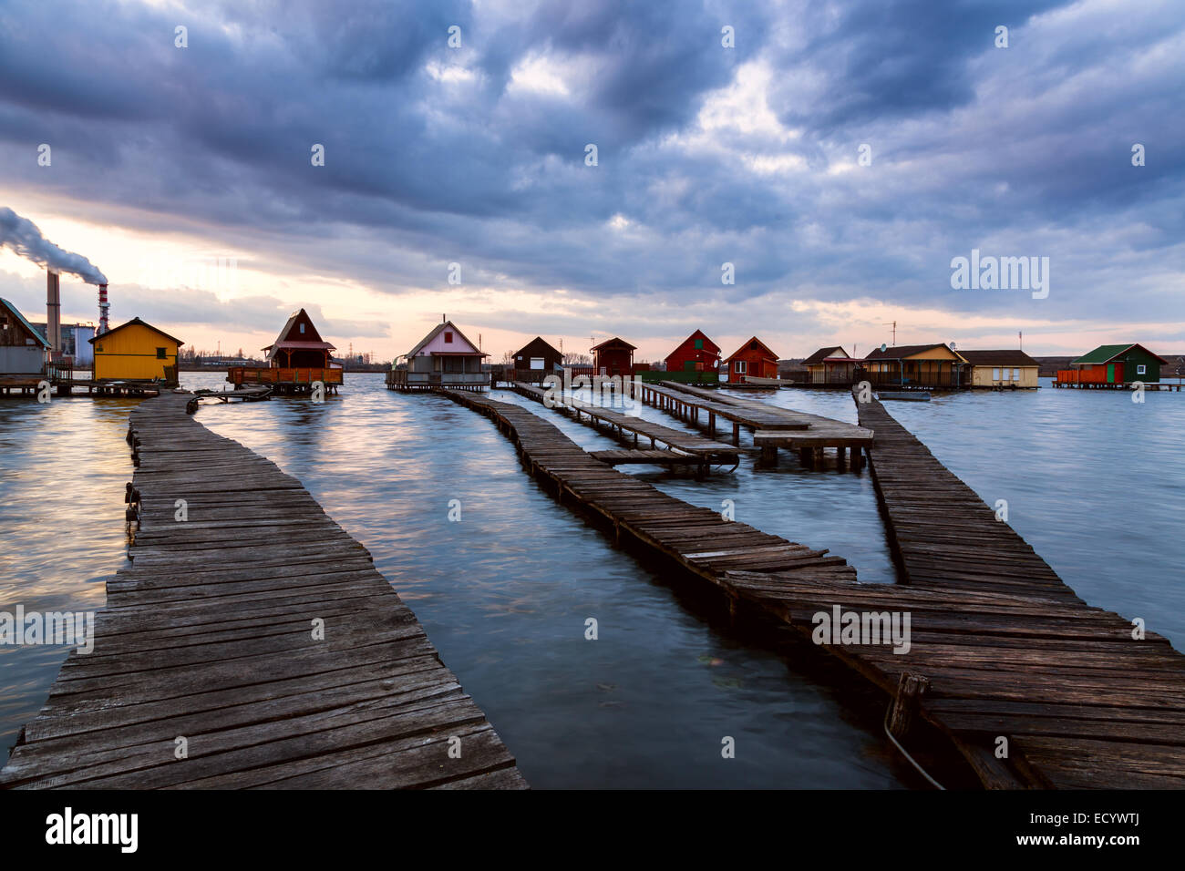 Sunset lake Bokod with pier and fishing wooden cottages, power plant in ...