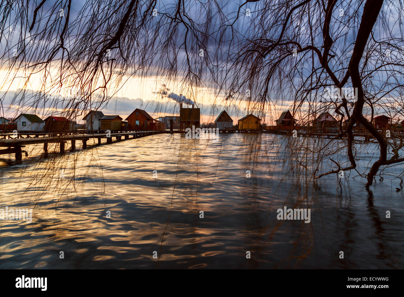Sunset lake Bokod with pier and fishing wooden cottages, power plant in ...