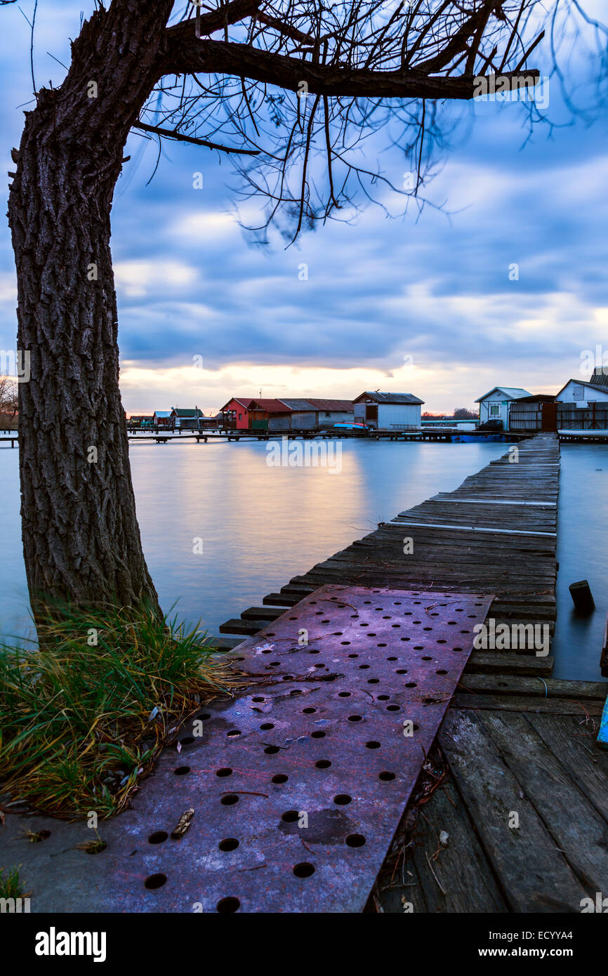 Sunset lake Bokod with pier and fishing wooden cottages, power plant in ...