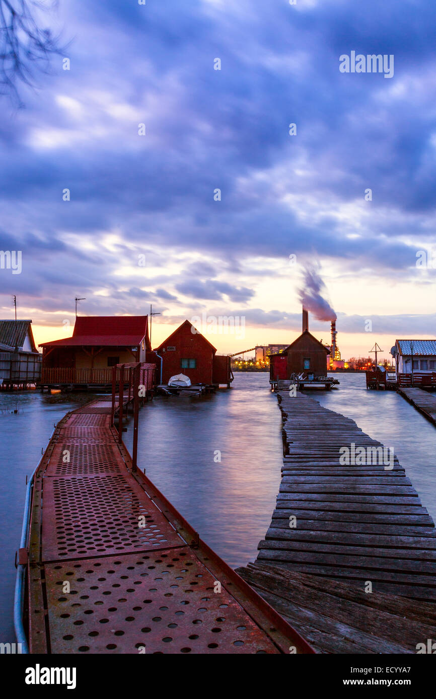 Sunset lake Bokod with pier and fishing wooden cottages, power plant in ...
