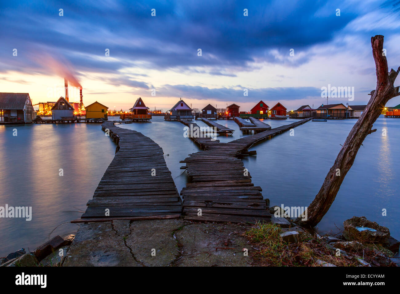 Sunset lake Bokod with pier and fishing wooden cottages, power plant in ...