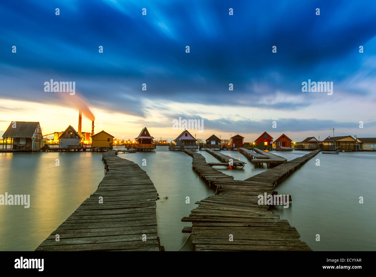Sunset lake Bokod with pier and fishing wooden cottages, power plant in ...