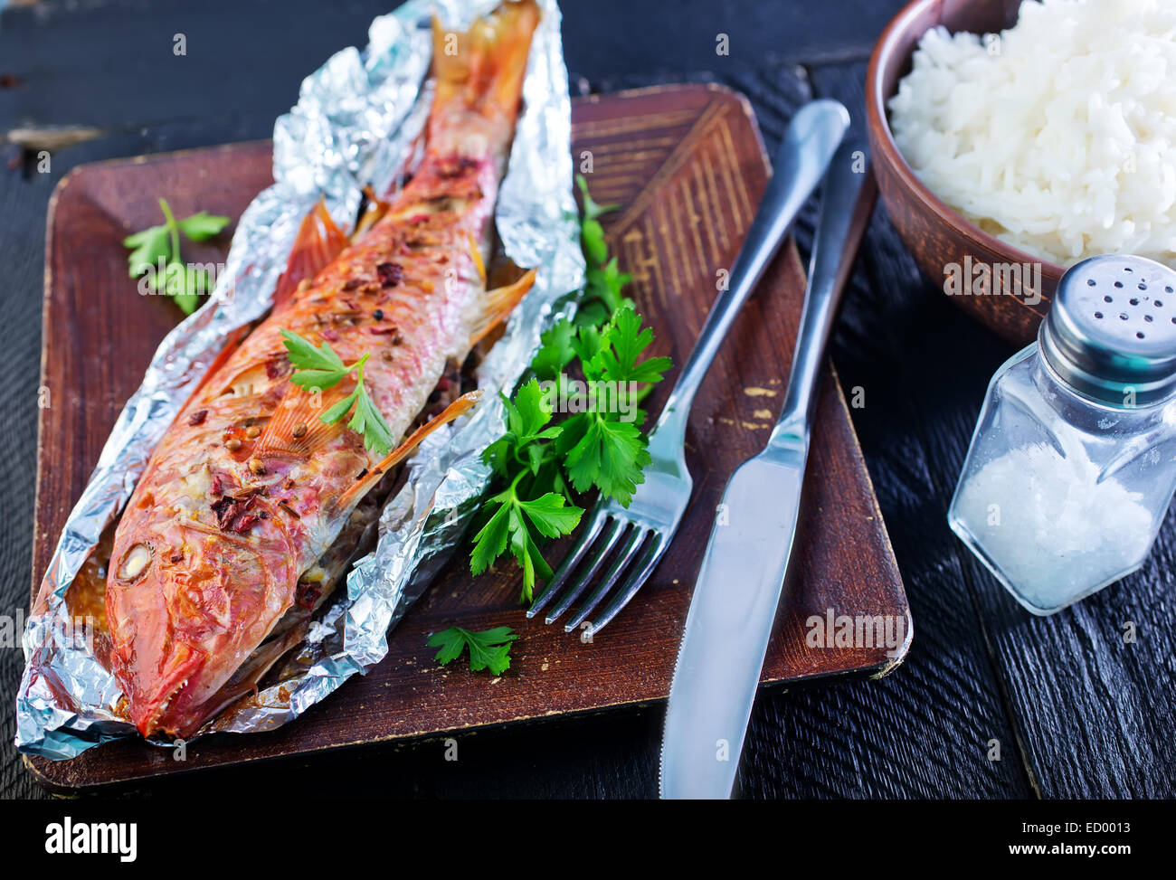 baked fish in the foil and on a table Stock Photo - Alamy