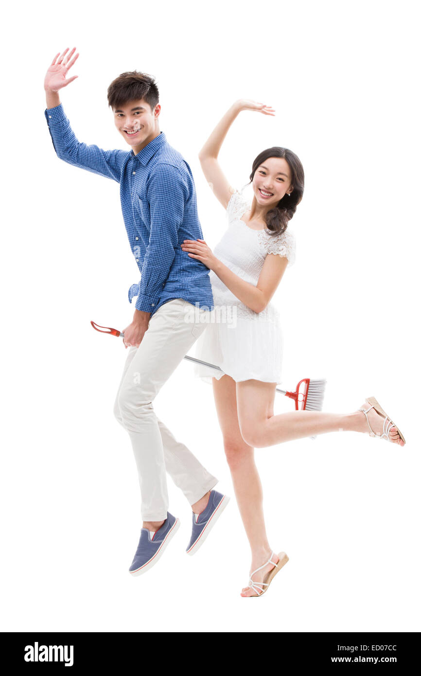 Happy young couple flying on broom Stock Photo - Alamy