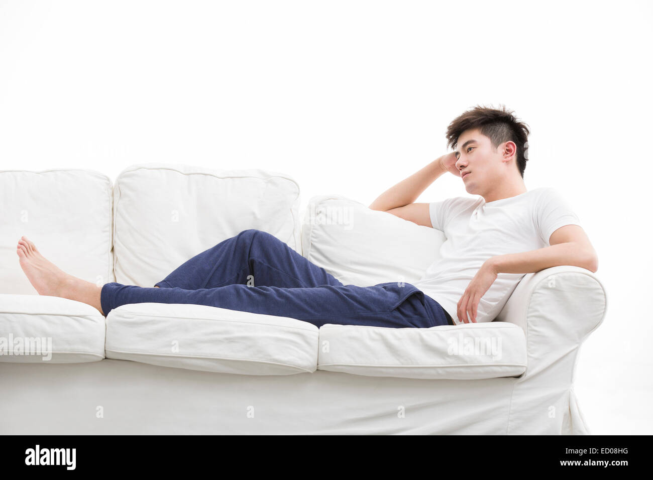 Young man thinking on couch Stock Photo - Alamy