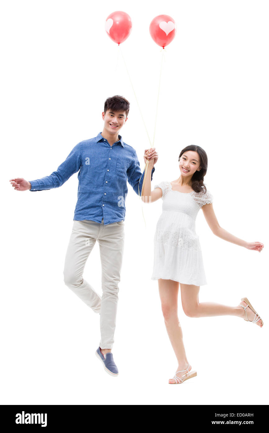 Happy young couple jumping with balloon Stock Photo - Alamy