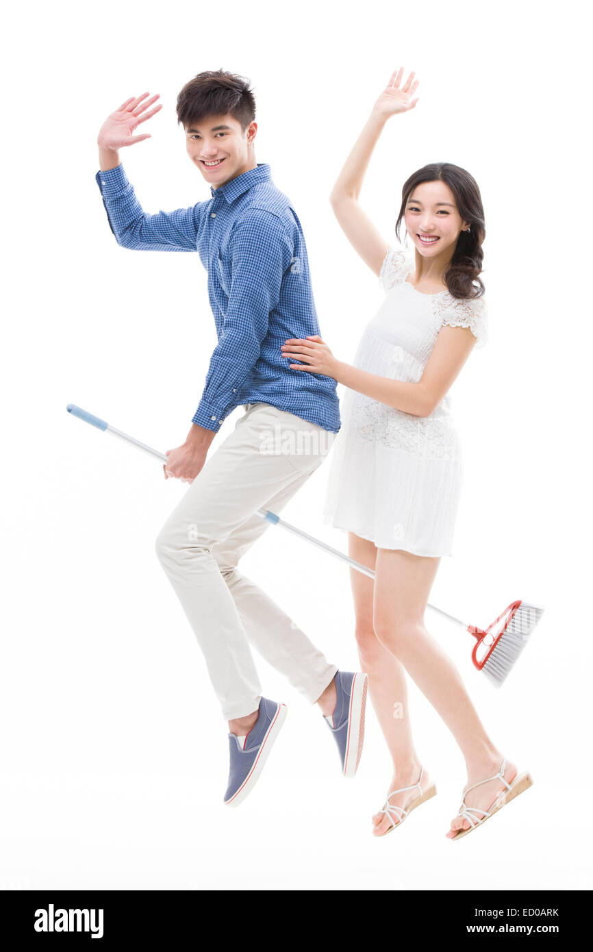 Happy young couple flying on broom Stock Photo - Alamy