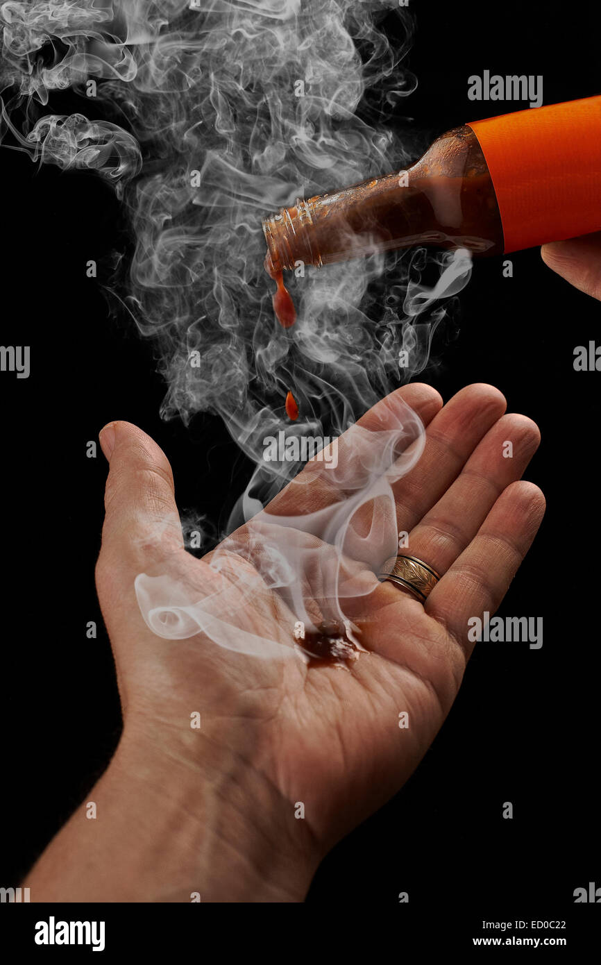 Hot Sauce dripping on human hand and smoking Stock Photo - Alamy