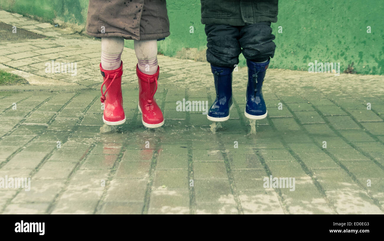 Two children jumping in puddle Stock Photo - Alamy