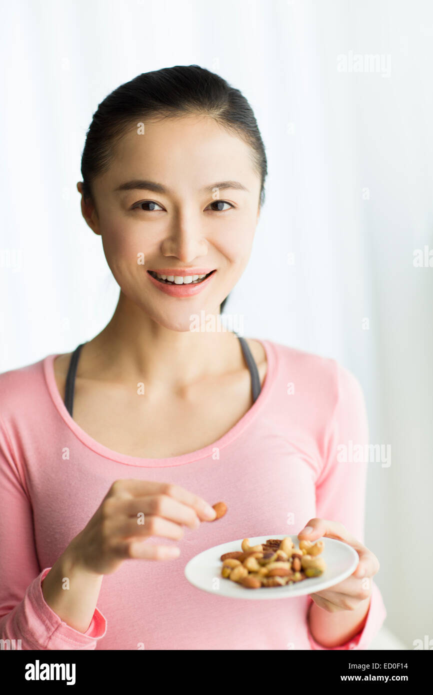 Happy young woman eating nuts Stock Photo - Alamy