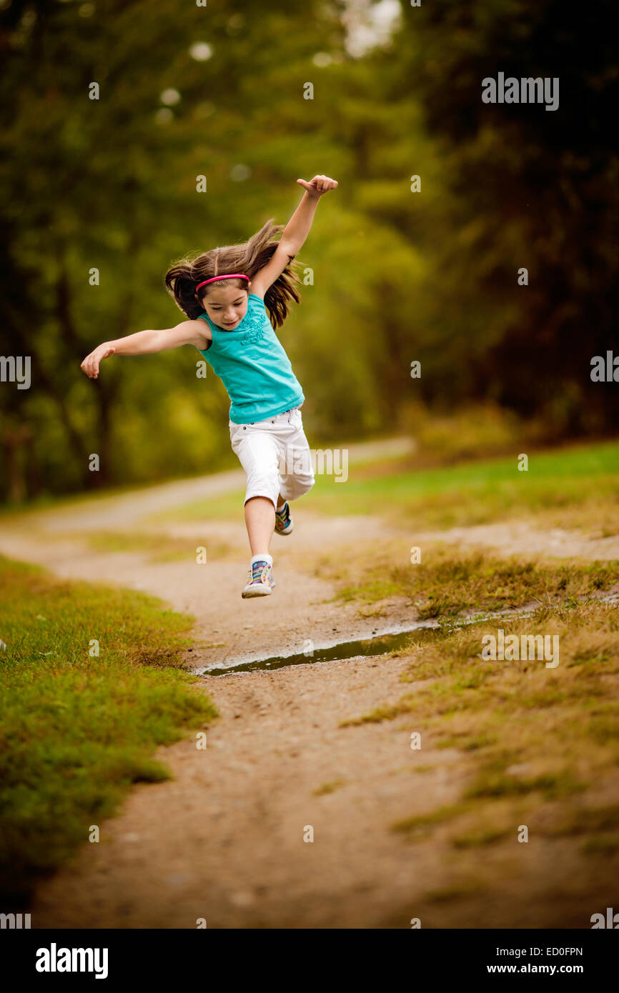 Girl jumping over puddle Stock Photo - Alamy