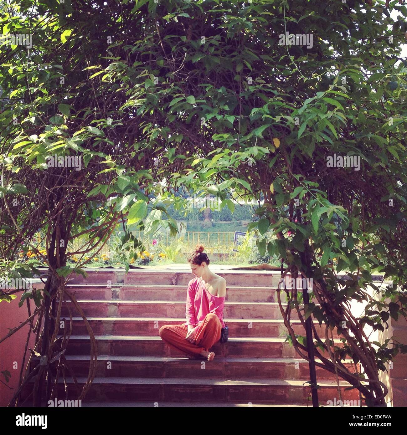 Young woman sitting on steps in garden, India Stock Photo - Alamy