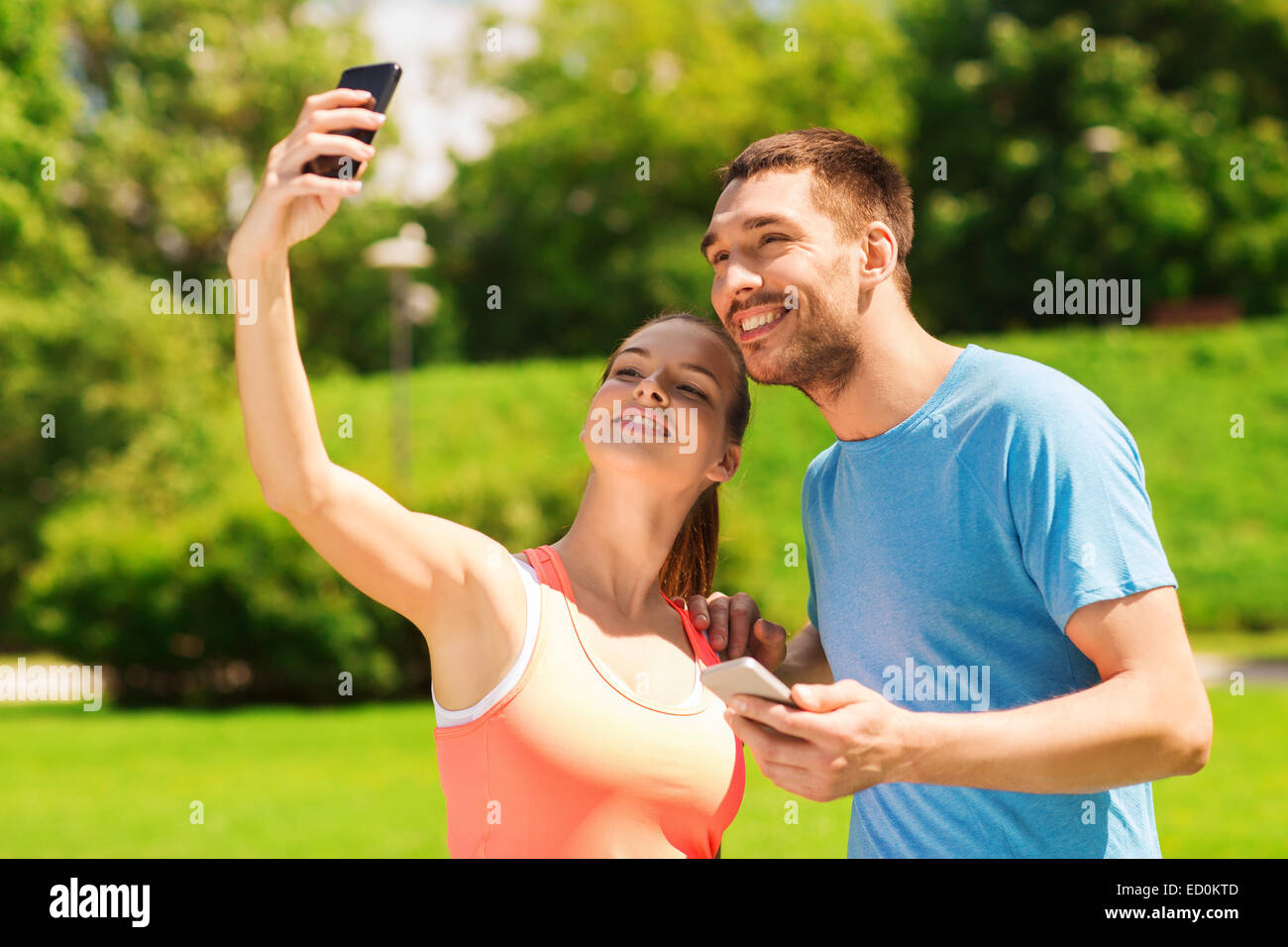 two smiling people with smartphones outdoors Stock Photo - Alamy