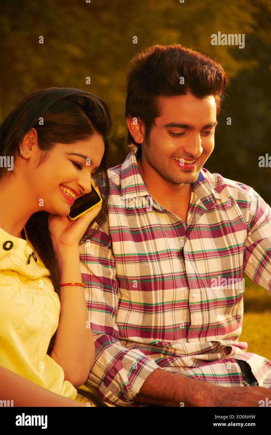 2 indian couple park talking phone Stock Photo - Alamy