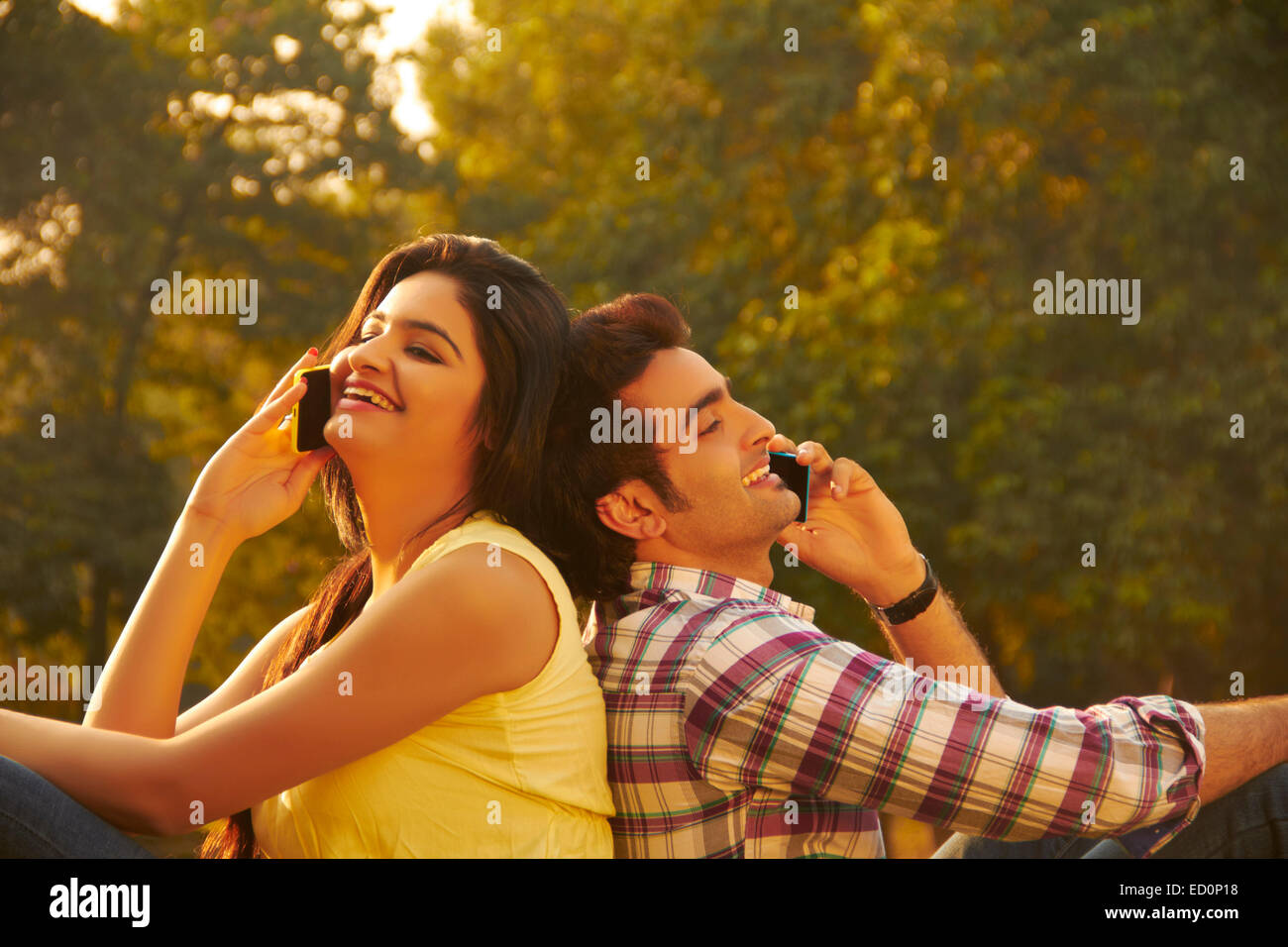 2 indian couple park talking phone Stock Photo - Alamy