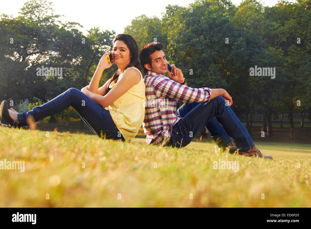 2 indian couple park talking phone Stock Photo - Alamy