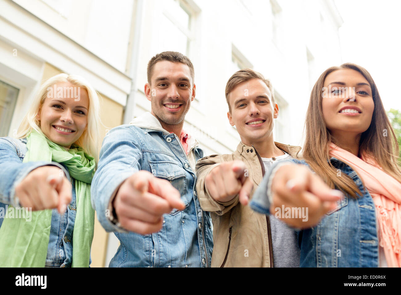 group of smiling friends in city pointing finger Stock Photo - Alamy