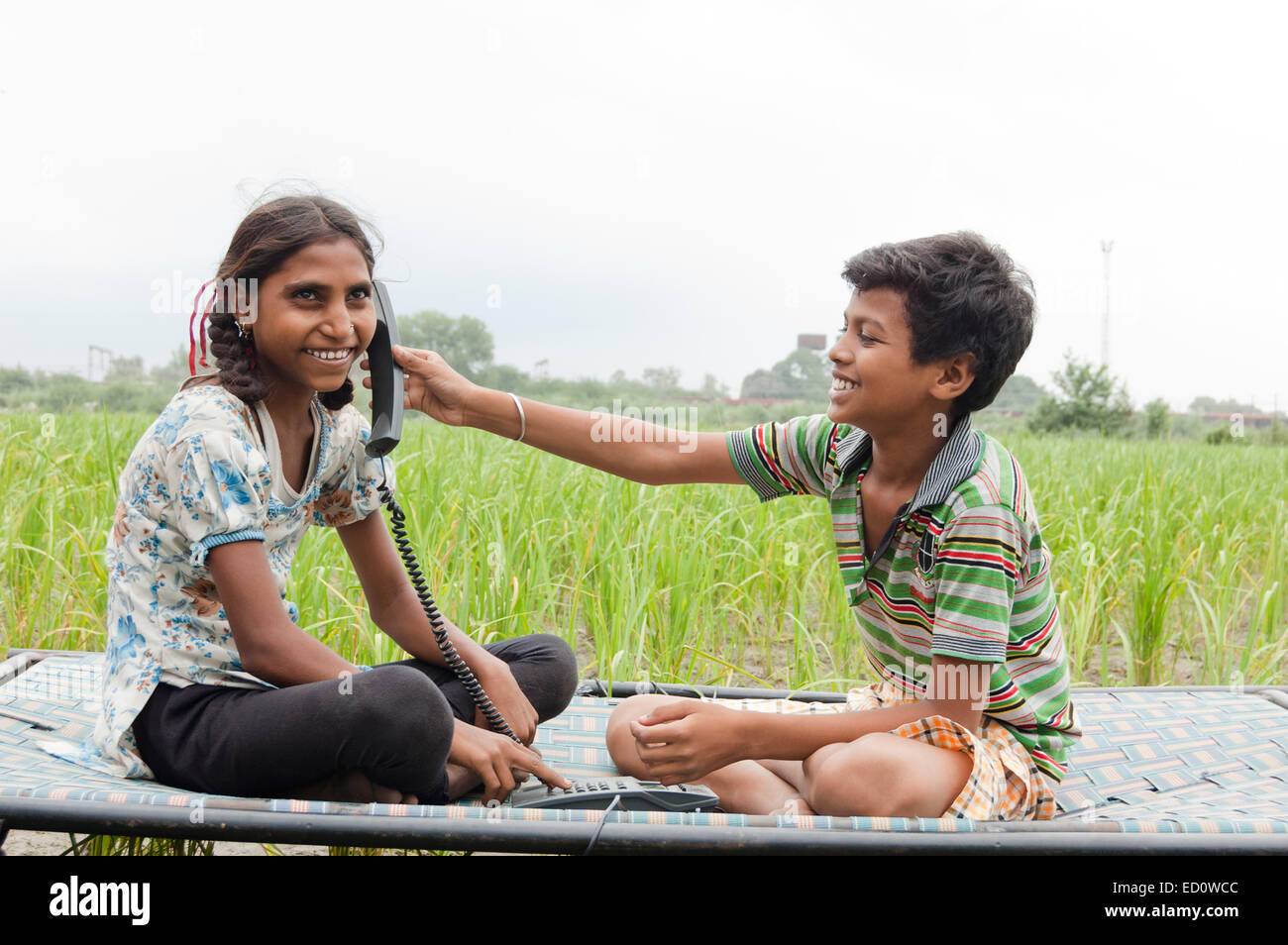 2 indian rural child field talking phone Stock Photo - Alamy