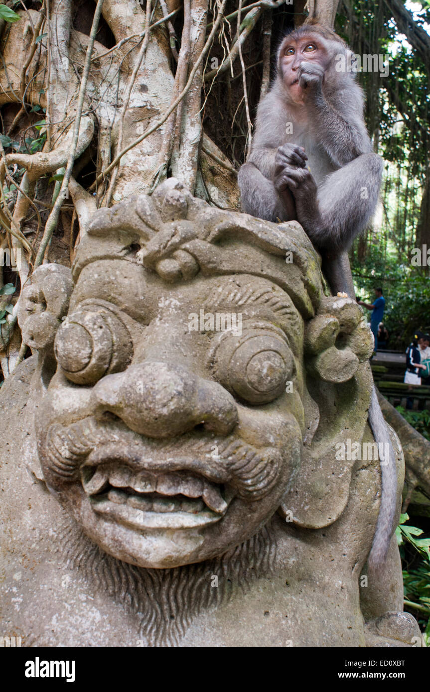 Monkeys having fun on stone statues of Hindu Holy Monkey Forest. Ubud ...