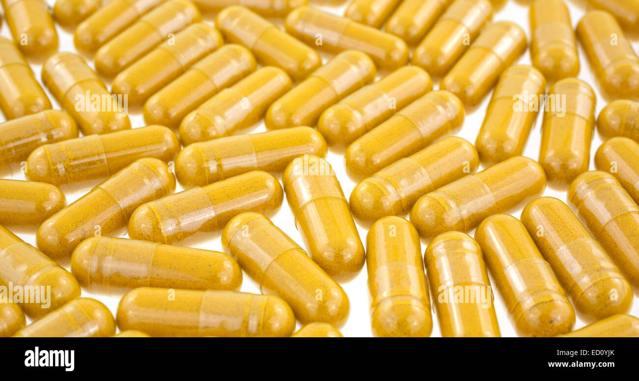 A layer of turmeric herbal capsules on a white background Stock Photo ...