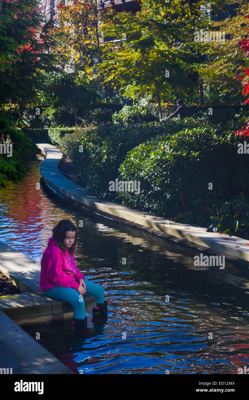 Child sitting by a decorative stream with her legs in the water Stock ...
