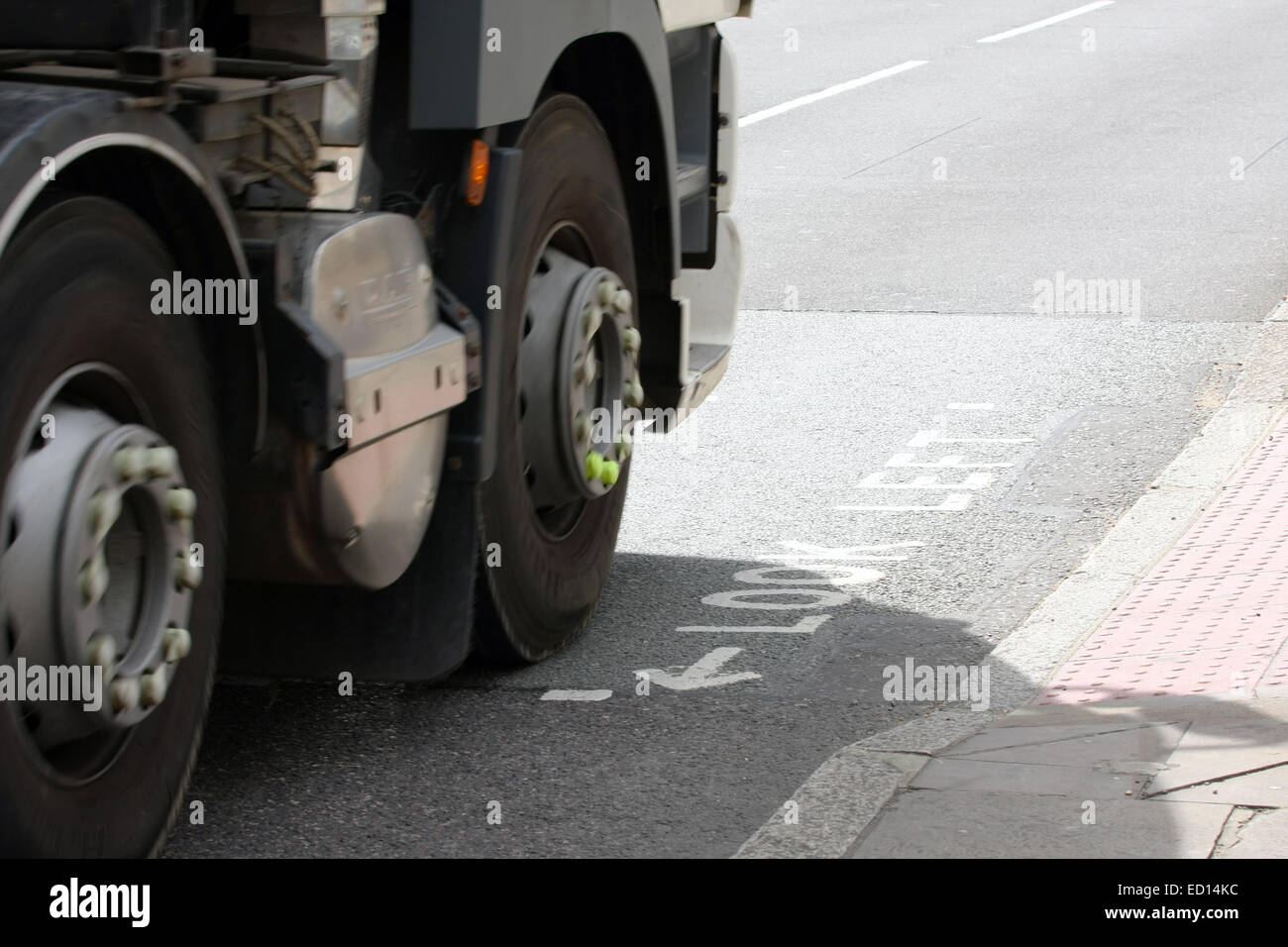 The front wheels of an articulated truck traveling passed a 'look left ...