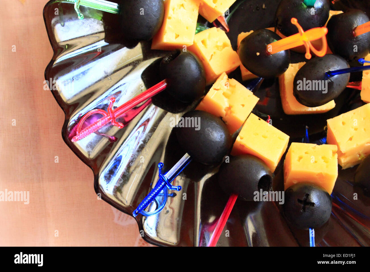 Multi-colored little swords with black olives and pieces of cheese ...