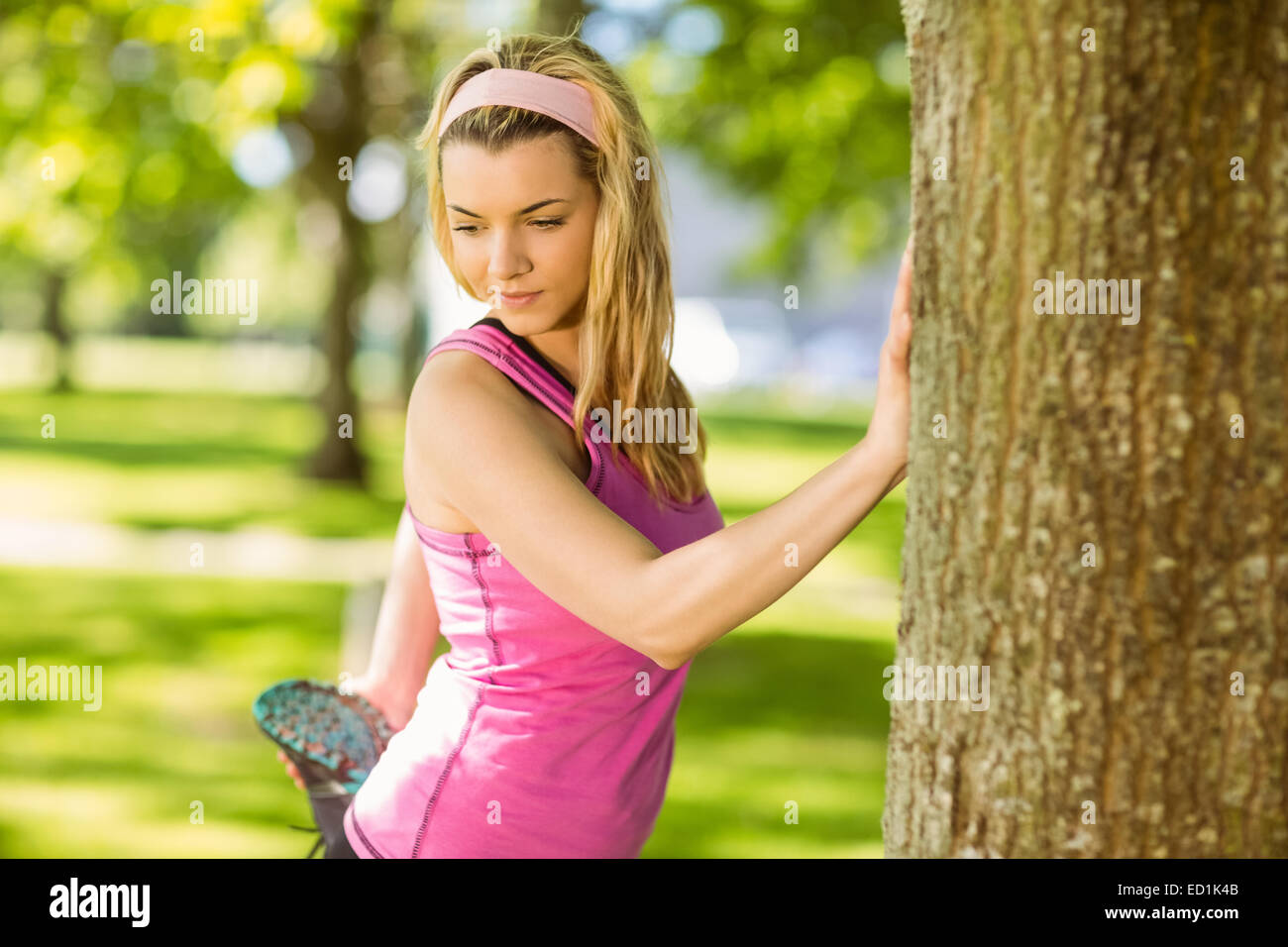 Fit blonde stretching against a tree Stock Photo - Alamy