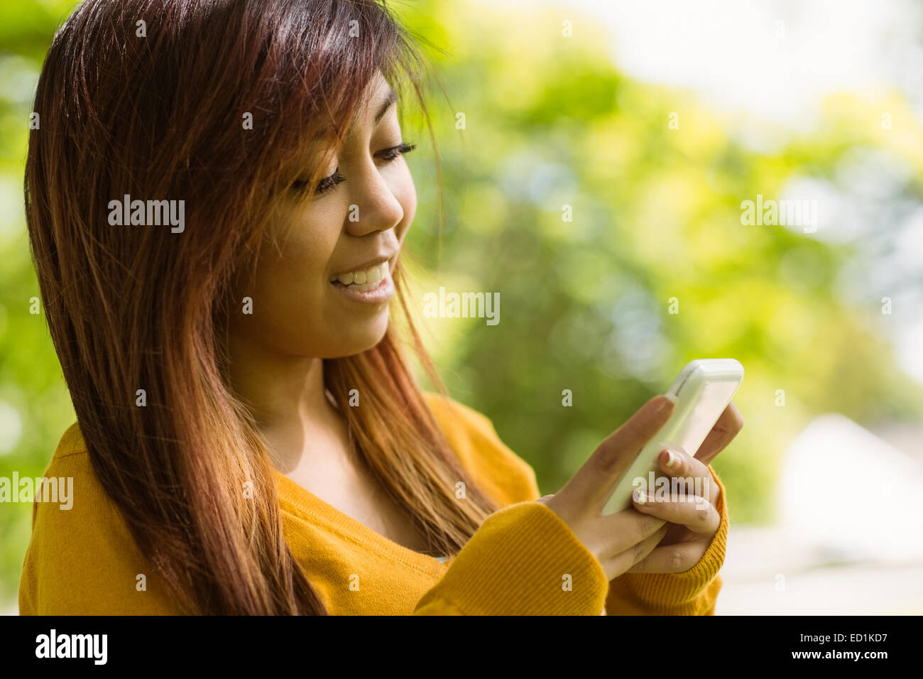 Beautiful woman text messaging in park Stock Photo - Alamy