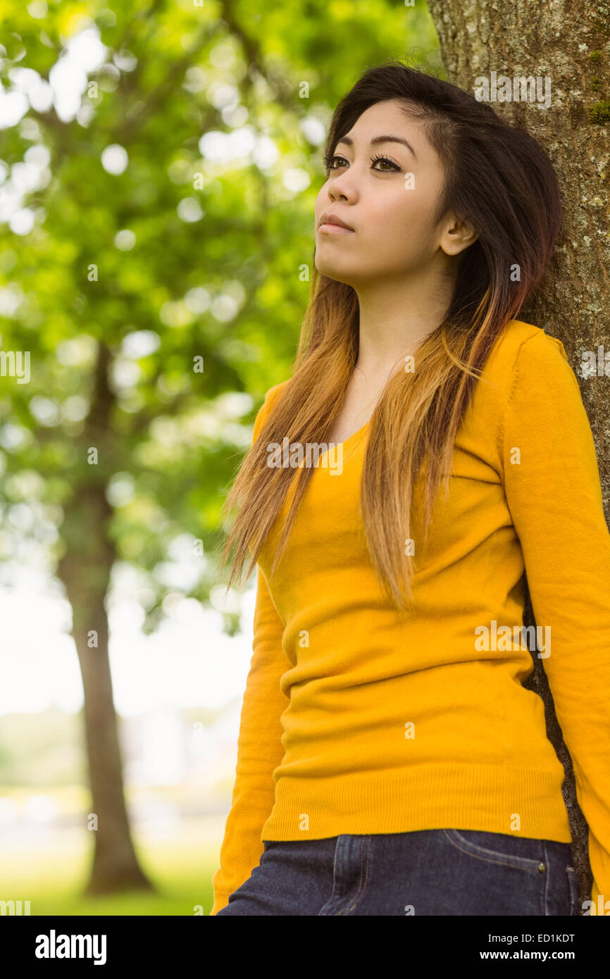 Beautiful woman standing against tree Stock Photo - Alamy