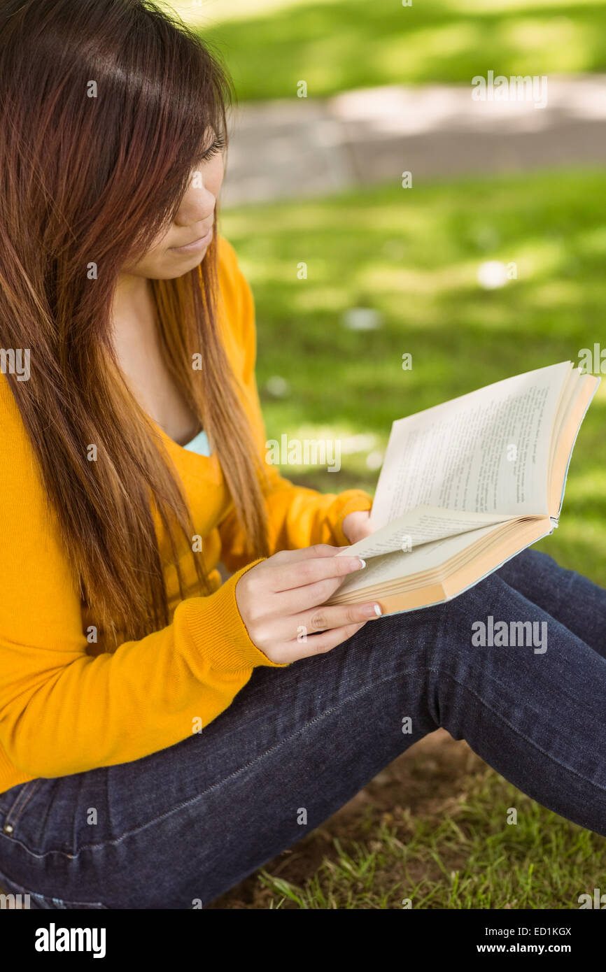 Relaxed female student reading book in park Stock Photo - Alamy