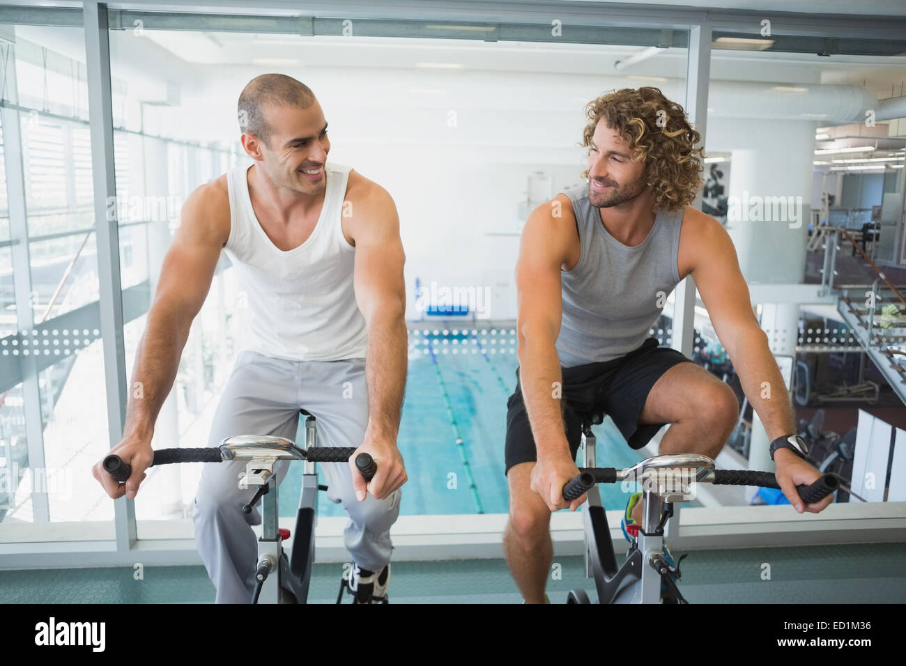 Fit men working on exercise bikes at gym Stock Photo - Alamy