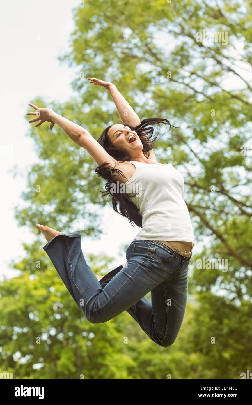 Excited brunette jumping in the park Stock Photo - Alamy