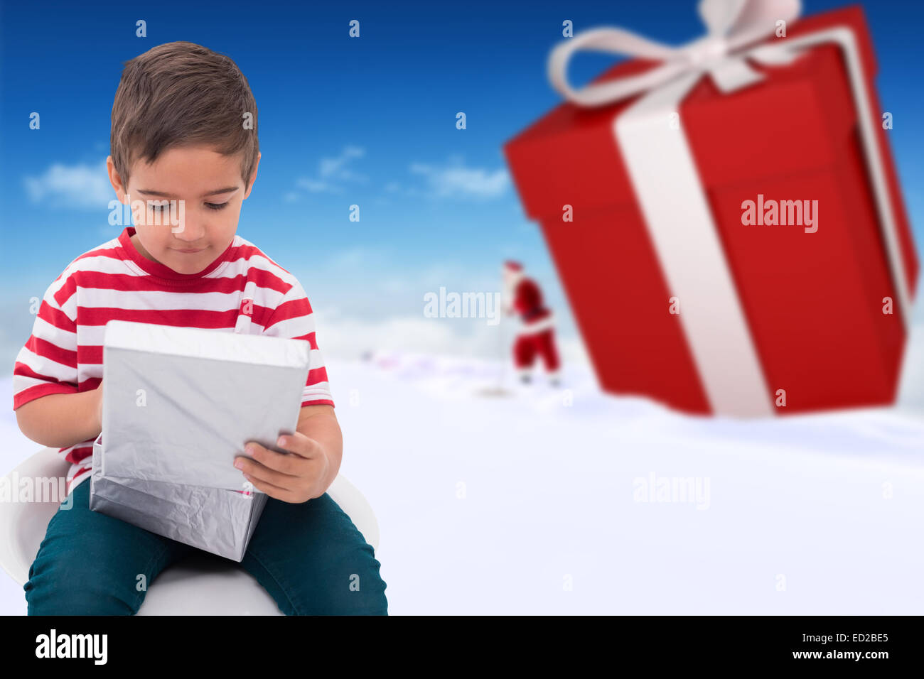 Composite image of cute little boy opening gift Stock Photo - Alamy