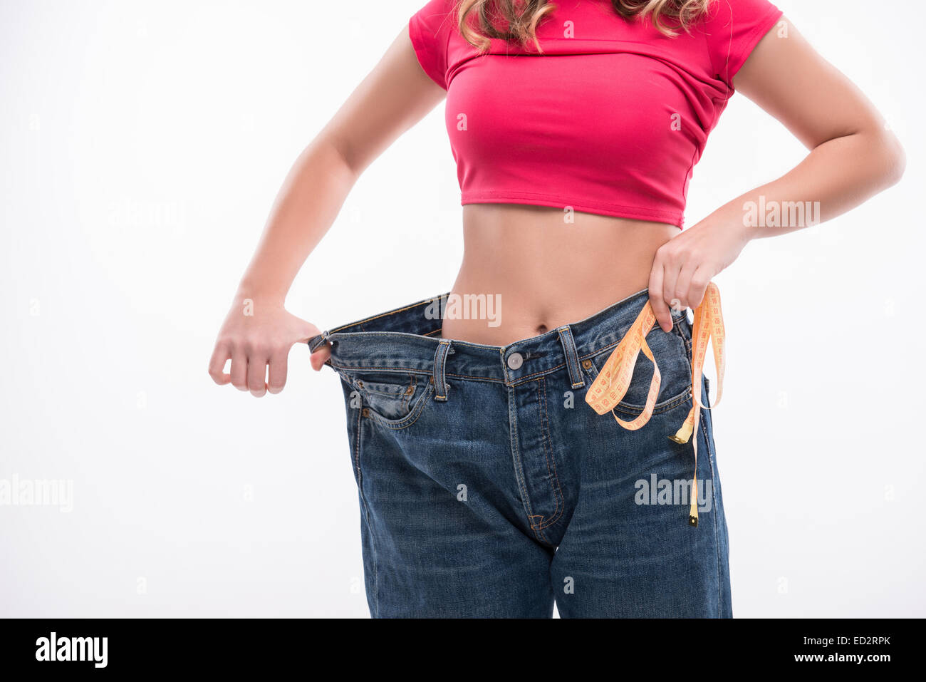 Slim waist of young woman in big jeans with measuring tape showi Stock ...