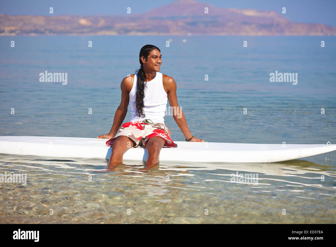 Young sporty man sitting on surfboard in low water Stock Photo - Alamy