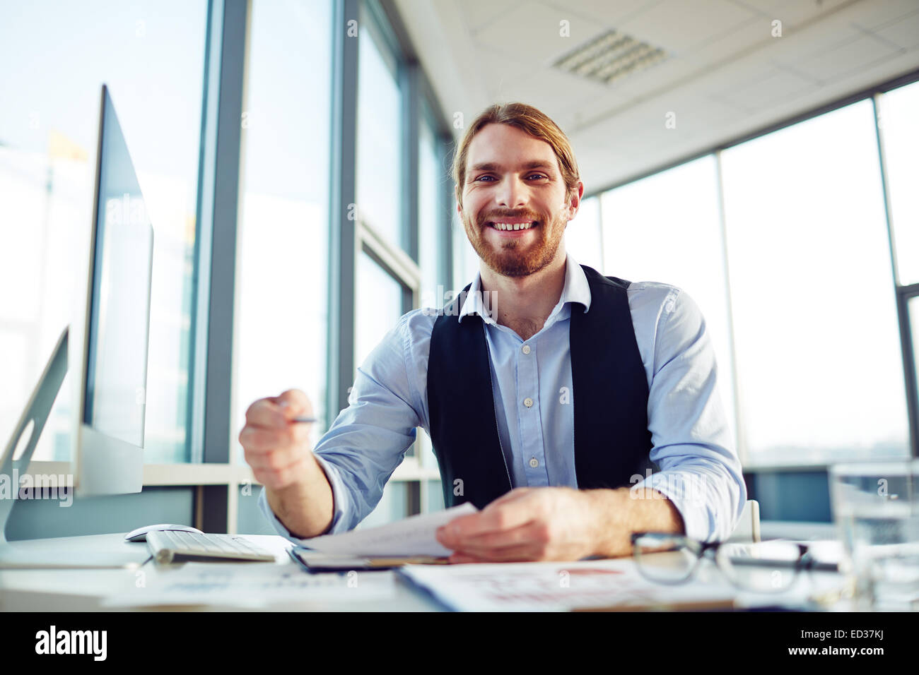 Cheerful office worker looking at camera at workplace Stock Photo - Alamy