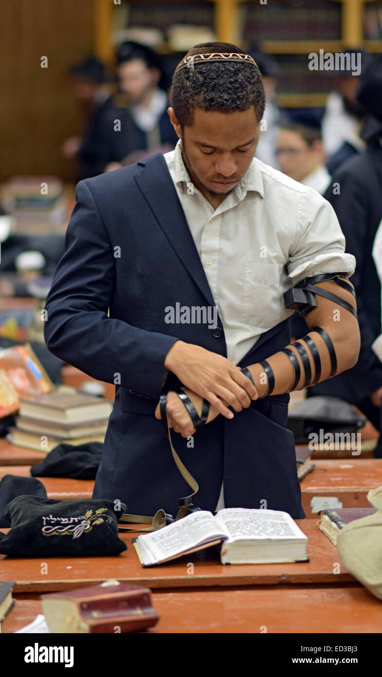 A young African American religious Jew putting on teffilin at a ...