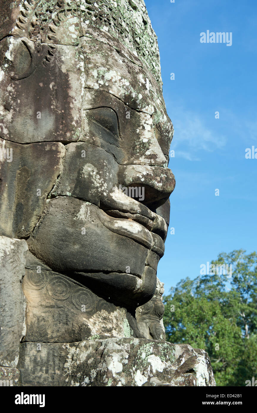 Bayon Temple stone face sculpture with green trees and blue sky at ...