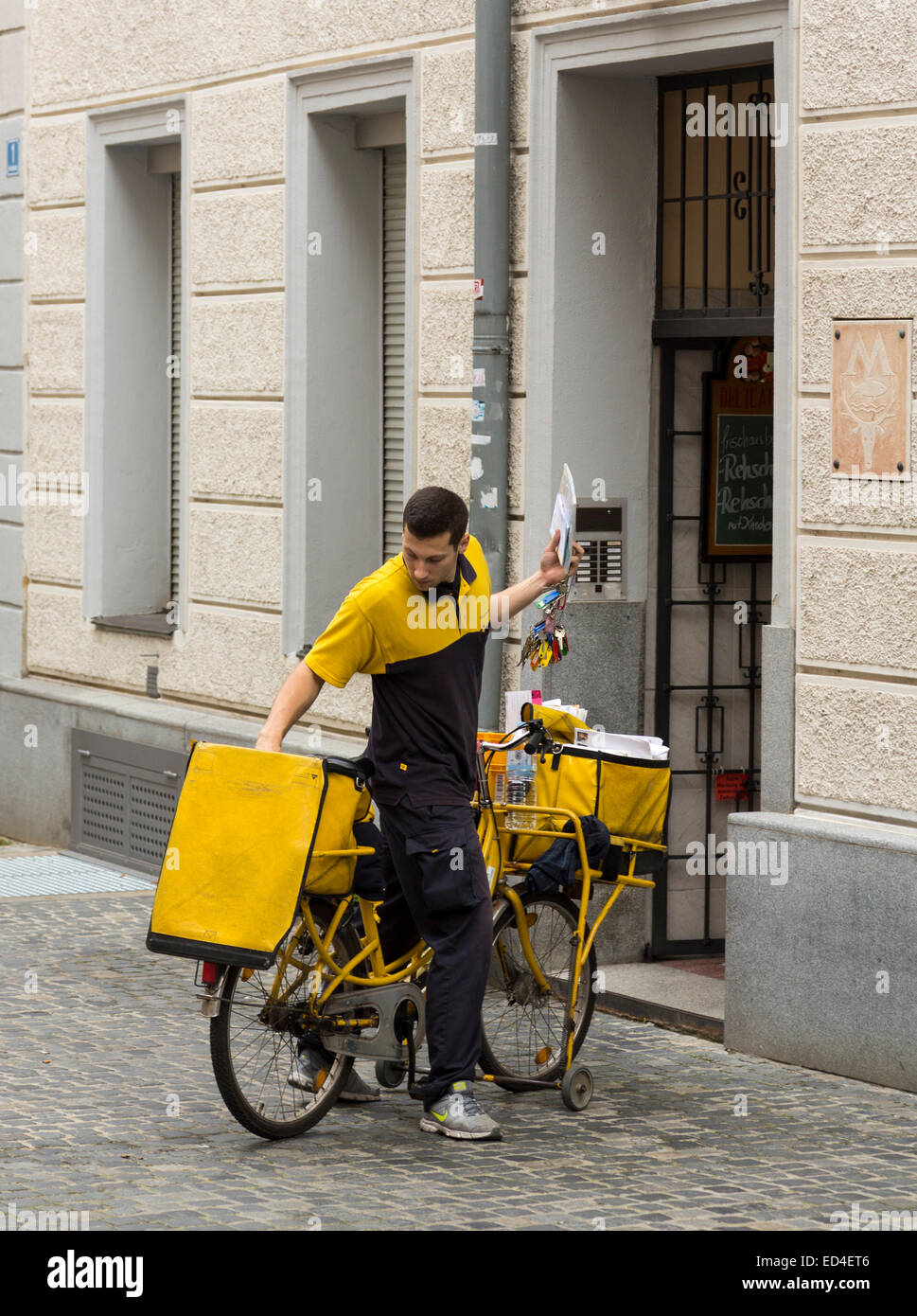 Postman delivering letters from bicycle in the medieval town of ...