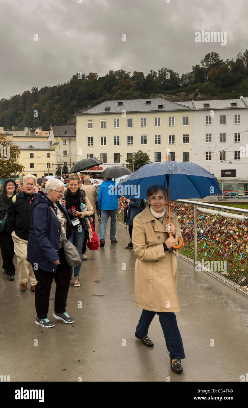 Tourists on pedestrian bridge in rain over river in Salzburg Austria ...