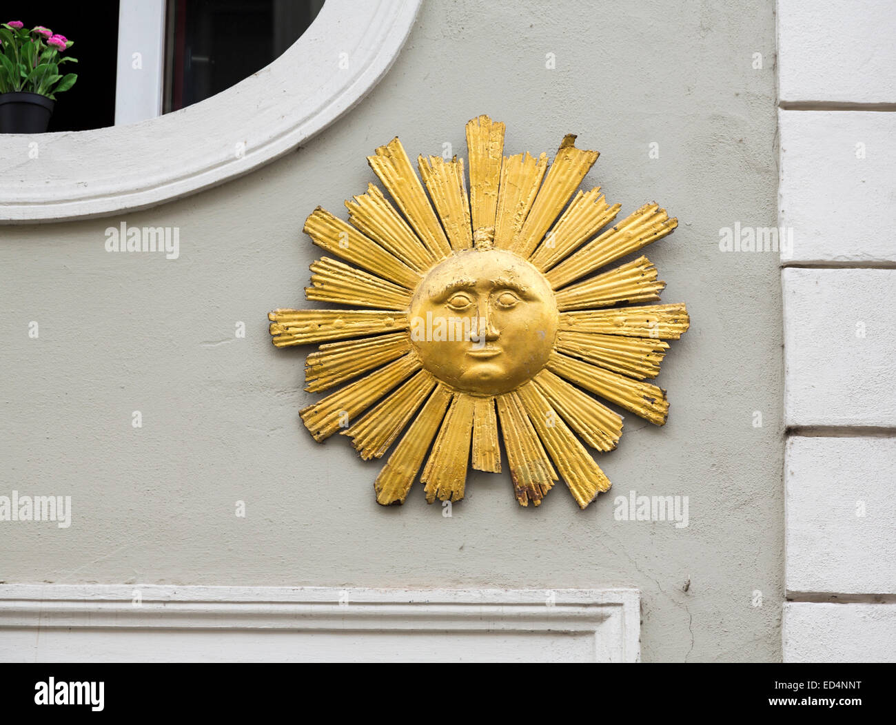 Gold colored wooden carving of the face of the sun with rays and ...